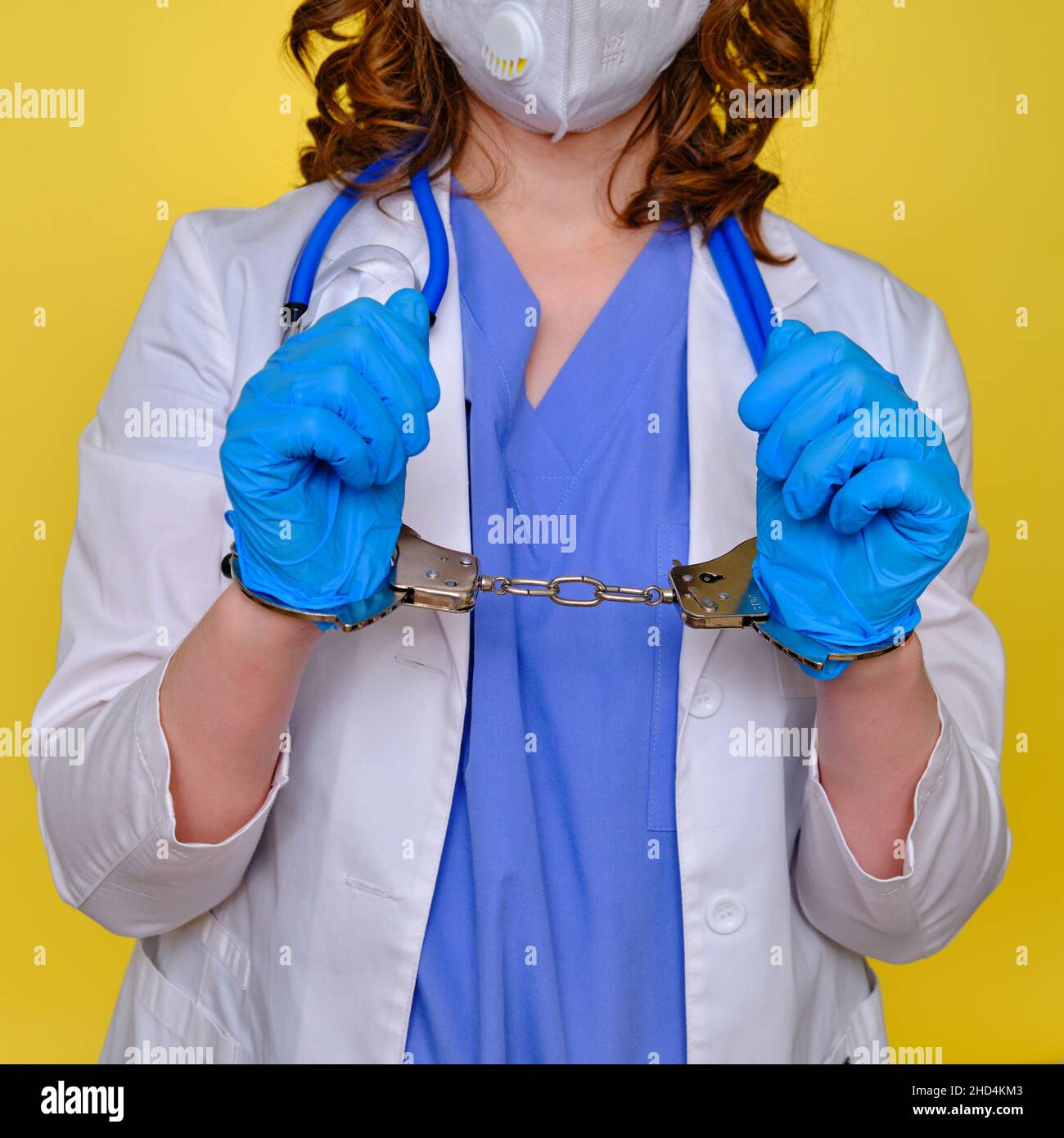 A doctor in a blue uniform with handcuffs on his hands, close-up. Medic ...