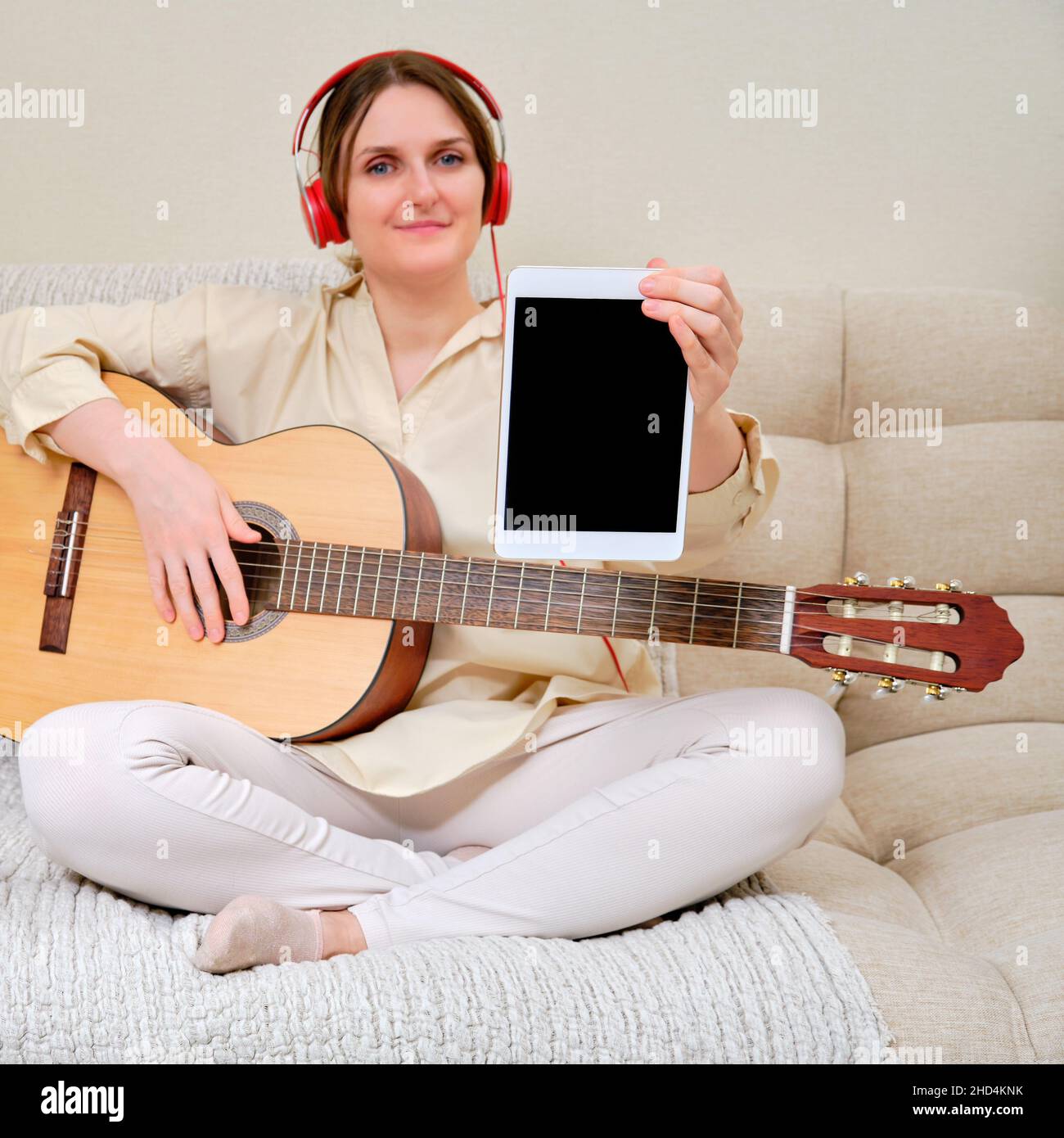 Happy woman musician with an acoustic guitar holds a tablet with a ...
