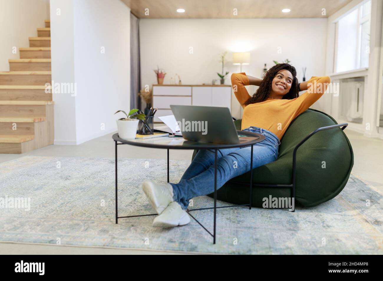 Smiling black woman leaning back sitting at desk Stock Photo - Alamy