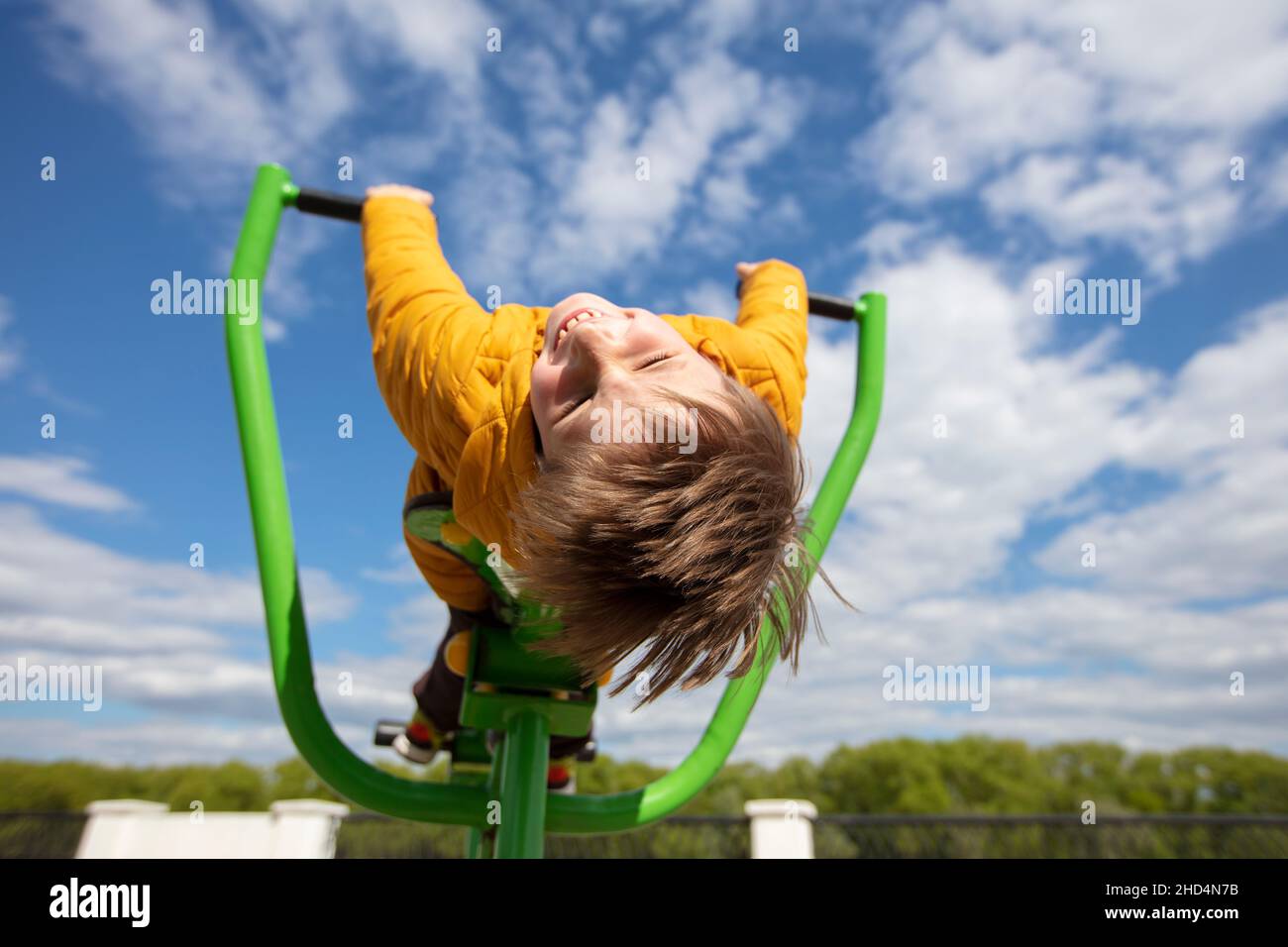 Funny little boy on a swing with his head down. Happy child for a walk ...