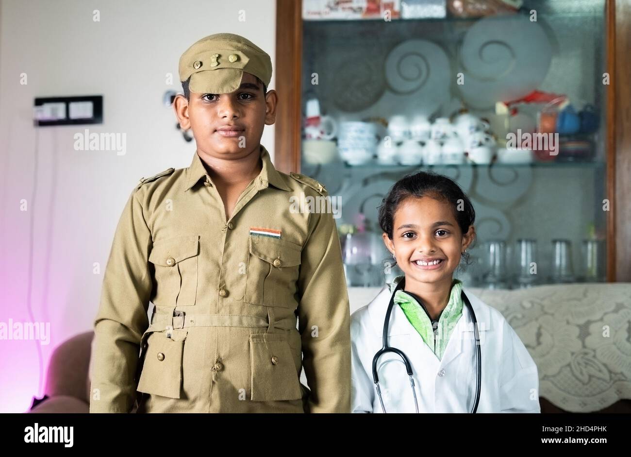 Siblings with Police and doctor costume looking camera at home ...