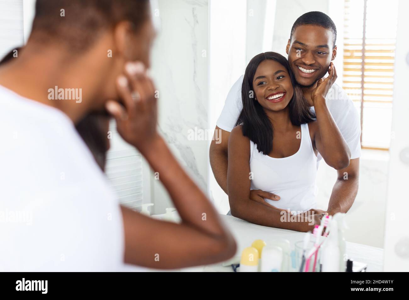 Happy Young Black Couple Looking At Mirror In bathroom And Embracing ...