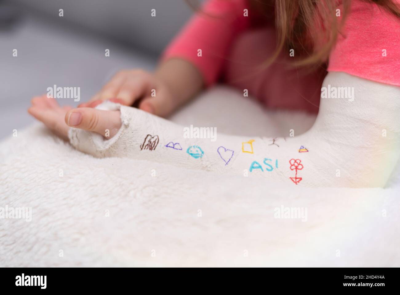 Girl's broken left arm has drawn a cute image on her arm on the plaster ...