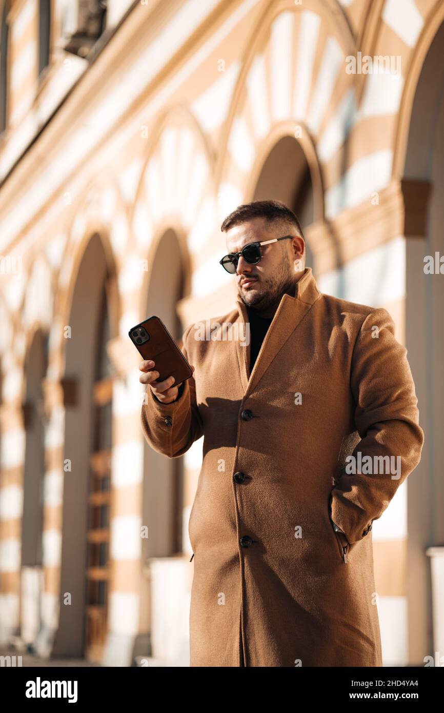 Shot of a Caucasian man using his phone next to a building in Bosnia ...
