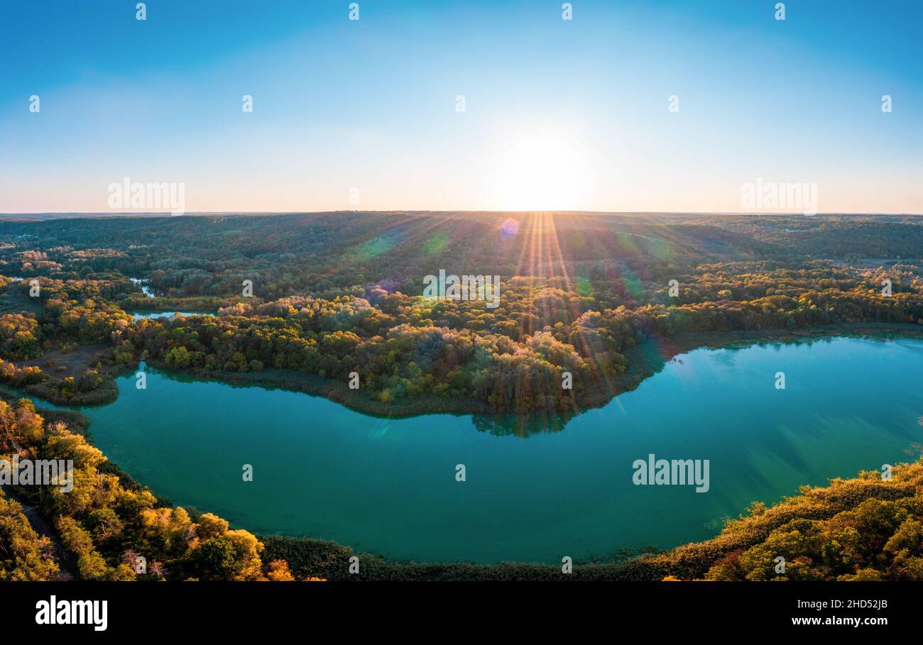Wide long river with blue calm water curves running across green trees ...