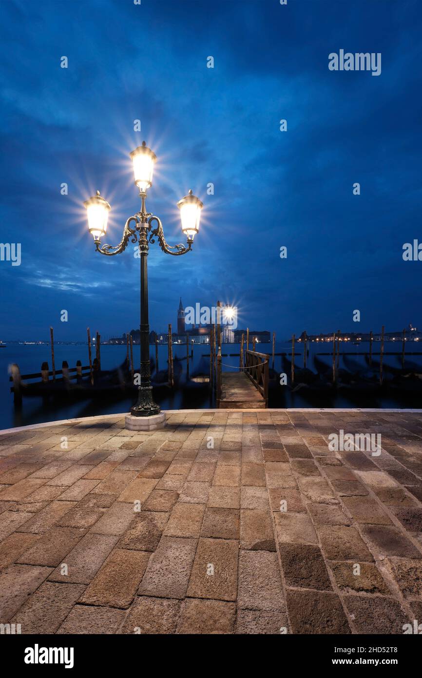 Italy, Venice Embankment at night. Historical lamp post with goldolas ...