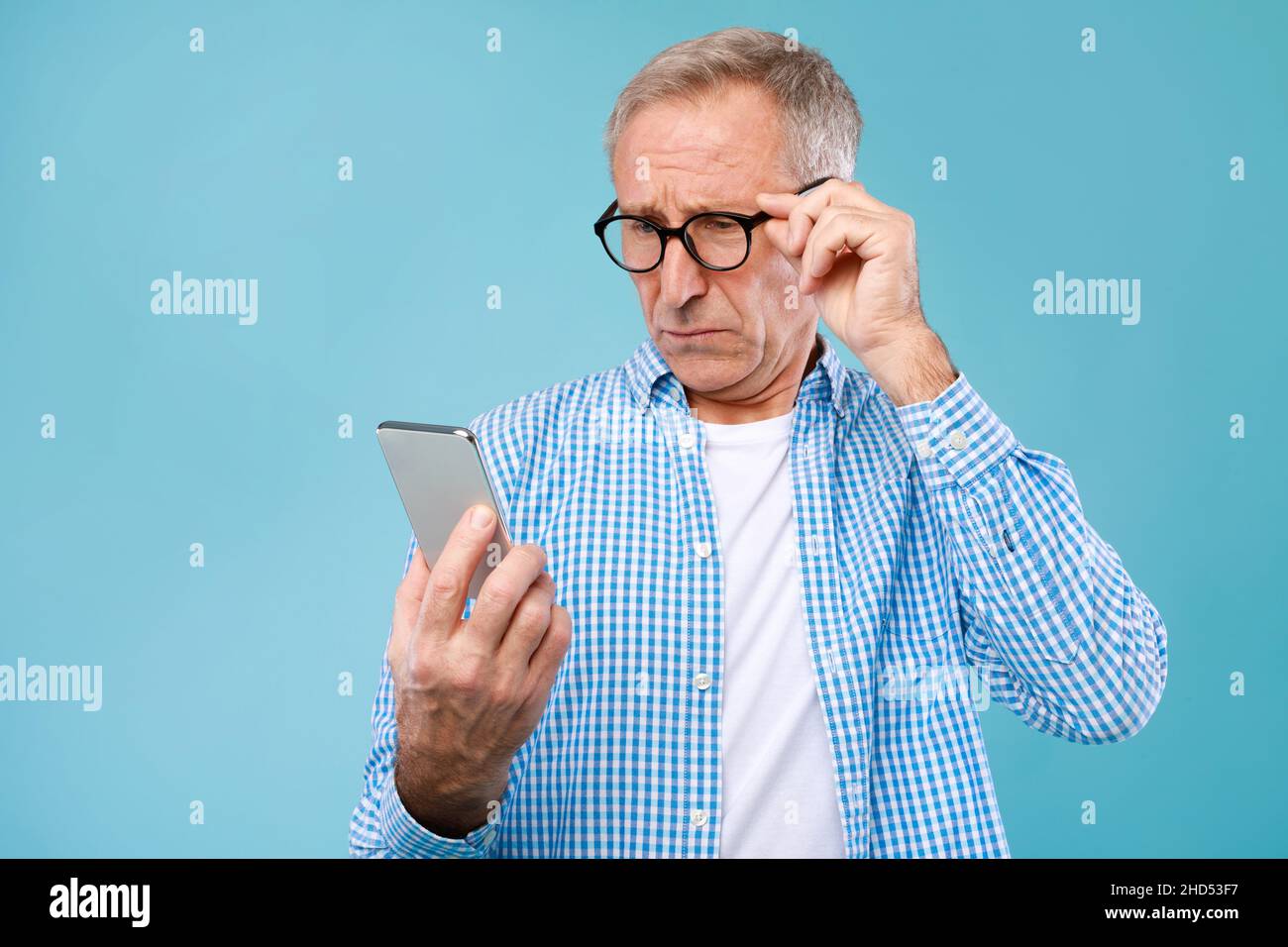 Mature man squinting using mobile phone, looking at screen Stock Photo ...