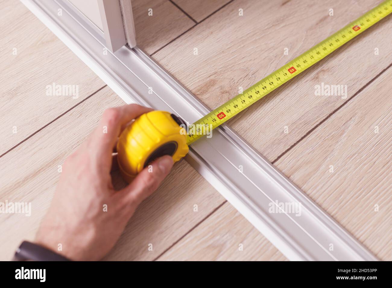 Tape measuring depth of sliding door wardrobe from wall to down rails ...