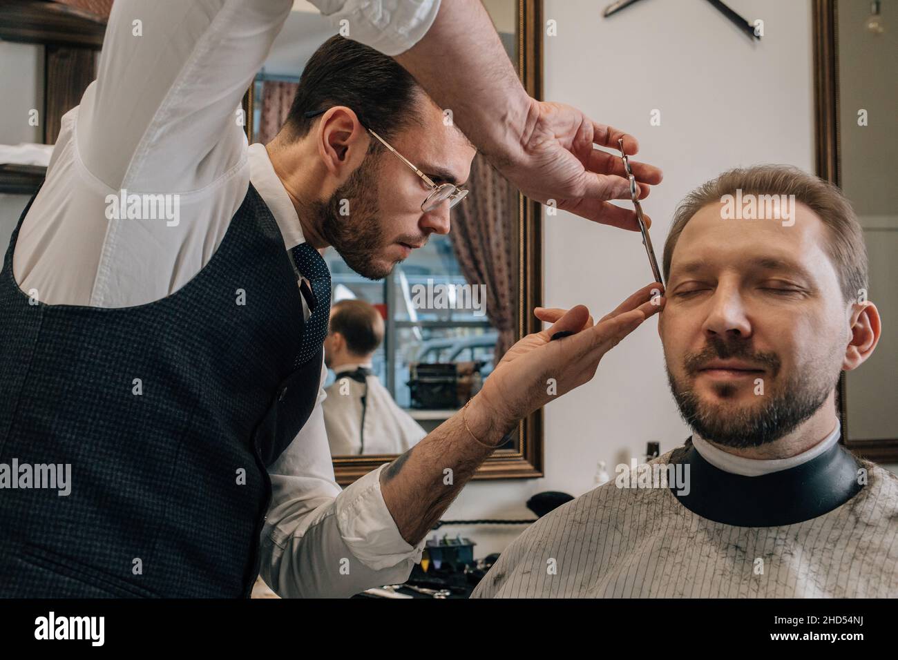 Barber in hairdressing salon cuts her hair with scissors Stock Photo ...