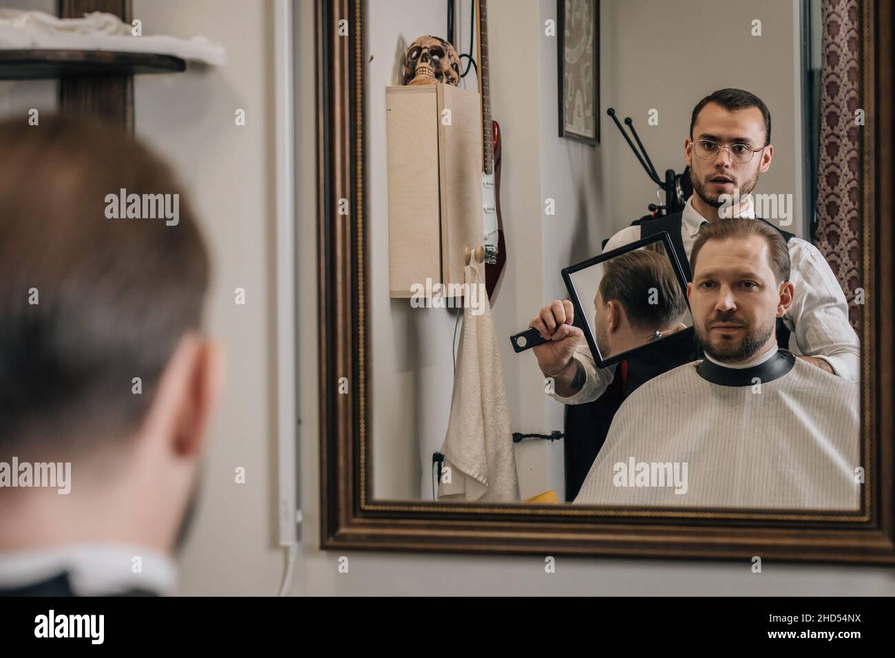 Barber shows client haircut from behind in reflection of mirror Stock ...