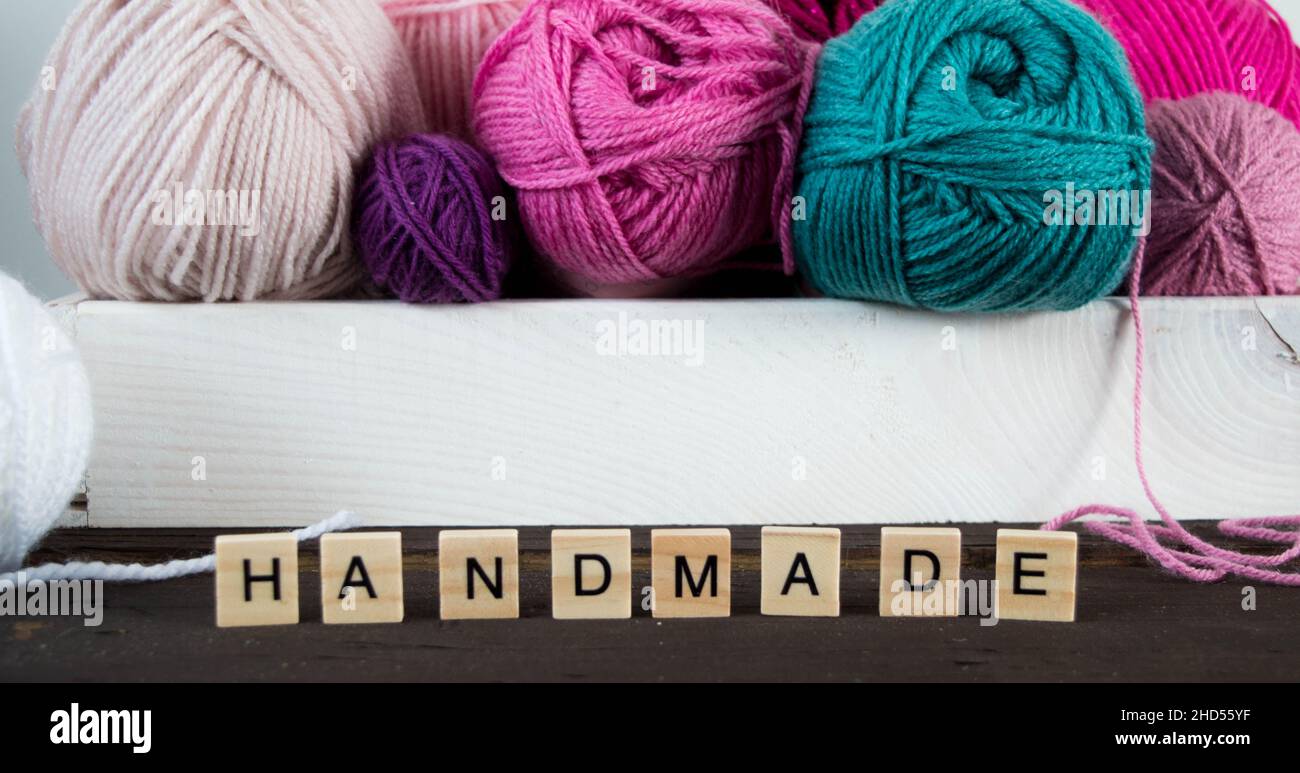colorful woolen balls on dark brown wooden ground for handicrafts ...