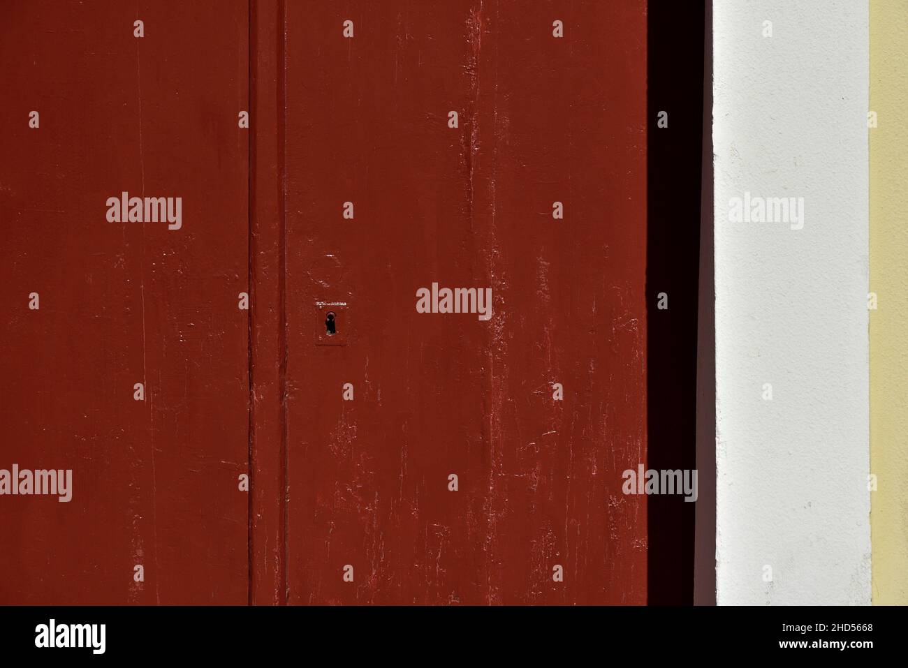 Antique Venetian red wooden door with white trim on an ochre wall in ...
