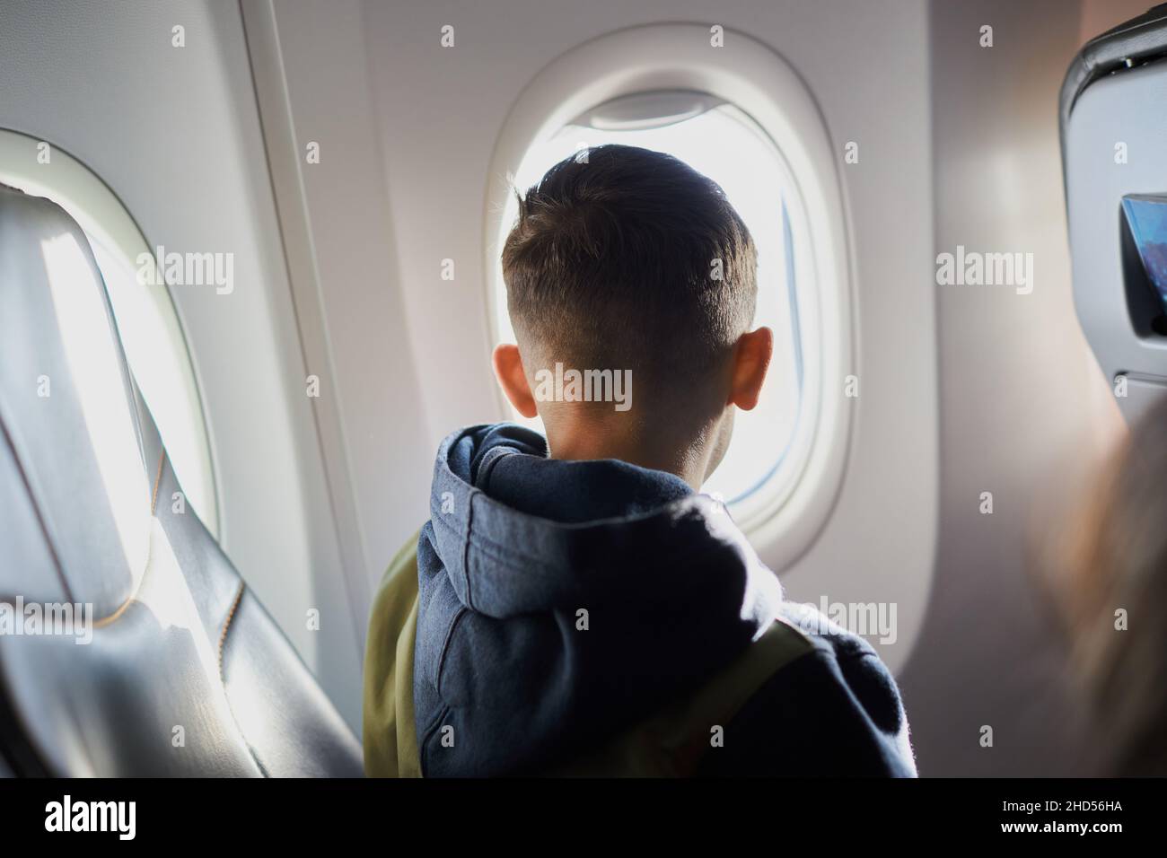 Caucasian boy is looking into the plane porthole during the flight ...