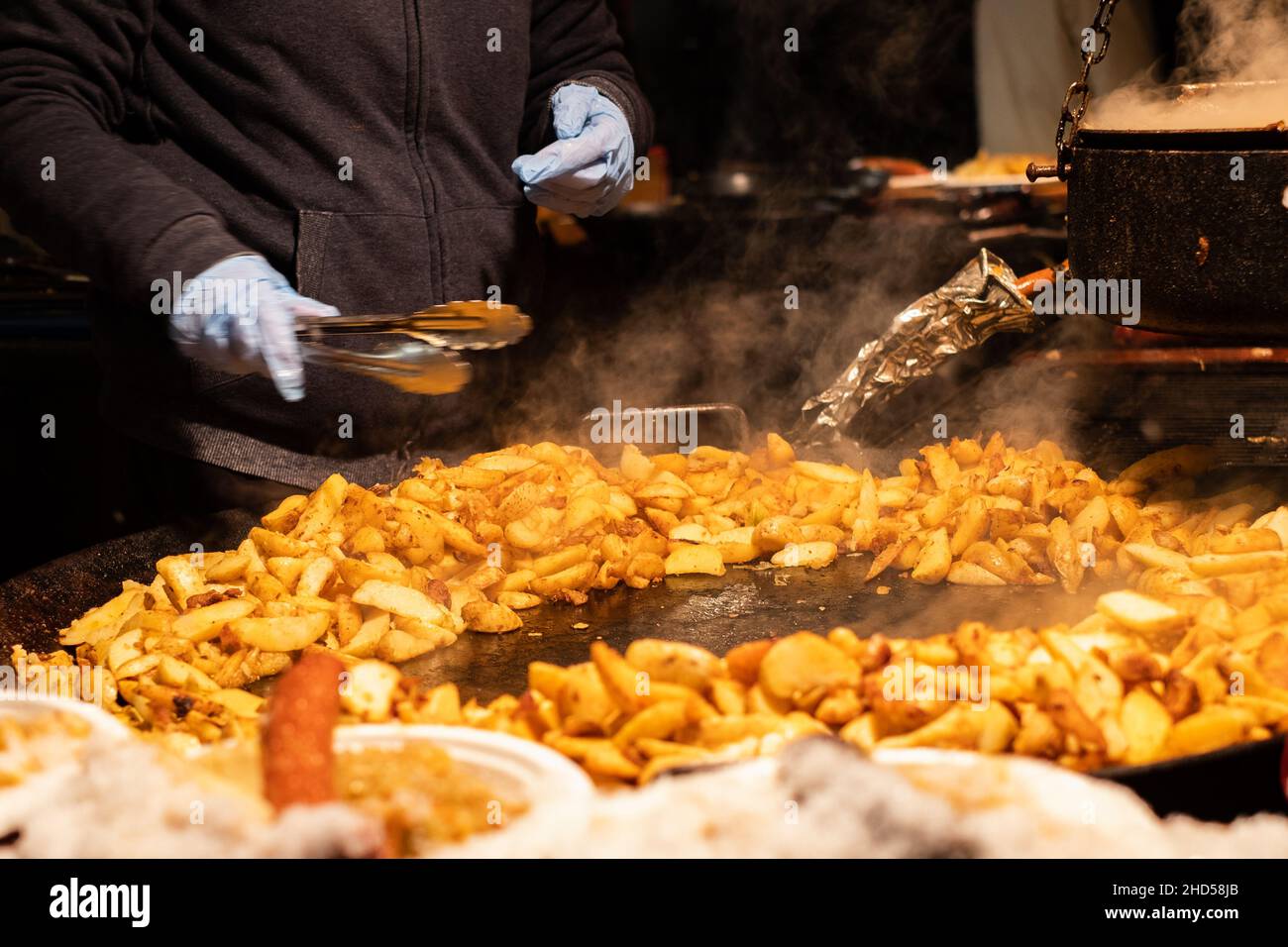 Fried potatoes on a large skillet. Street food during cold winter ...