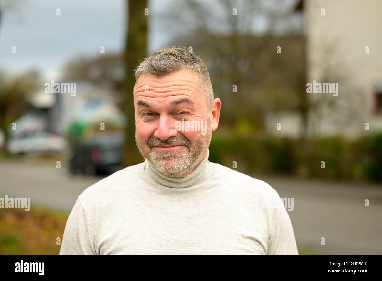 Charismatic man grinning at the camera in amusement with a knowing ...