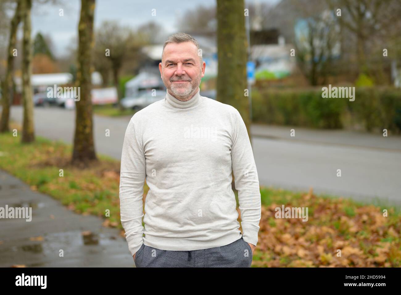 Attractive senior man with a happy friendly smile and relaxed stance ...