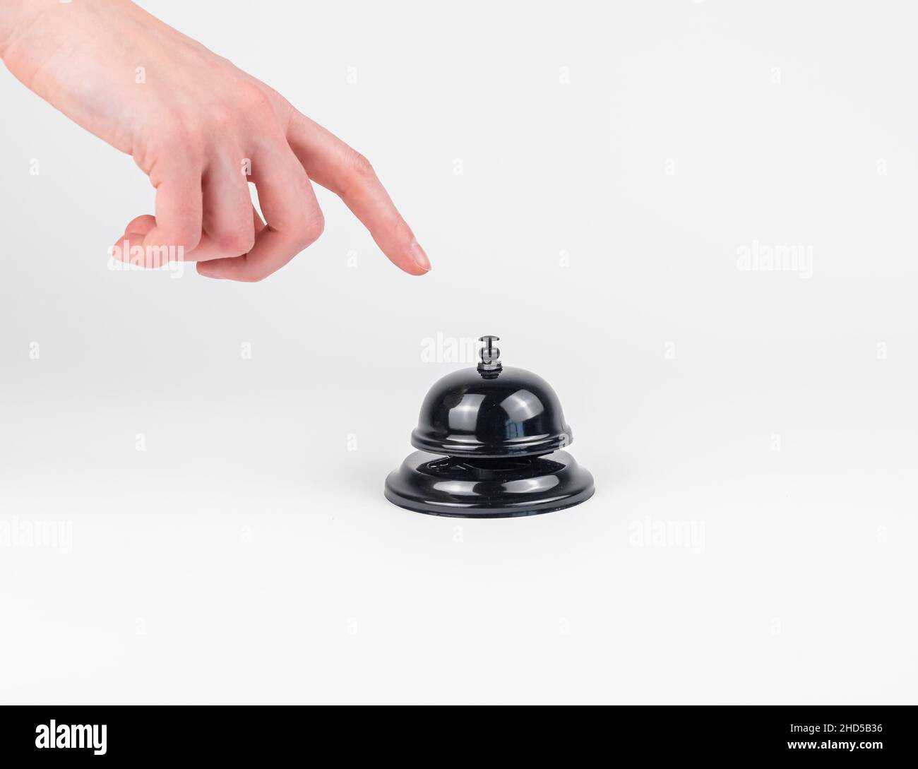 Desk bell is pressed by female hand. Concept image on white background ...
