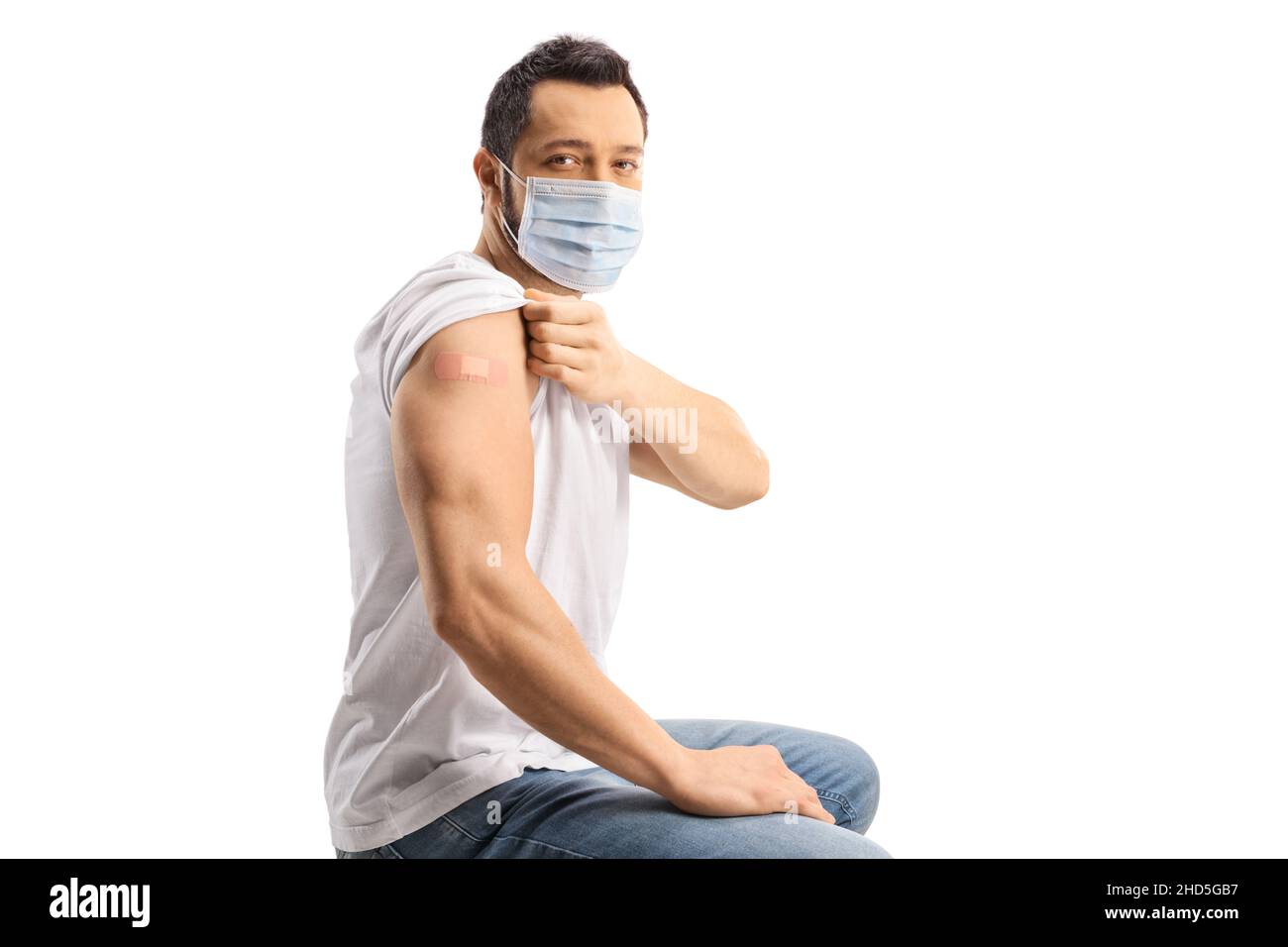 Young man with a mask showing his arm with a vaccine patch isolated on ...