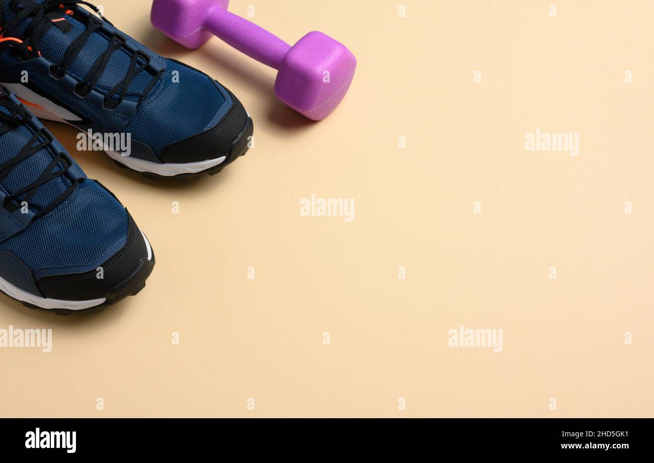 pair of blue sneakers and purple dumbbells on a beige background ...