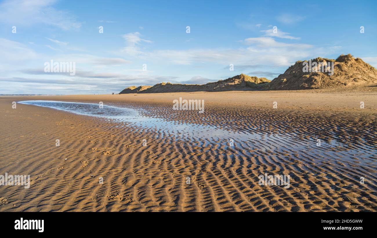 A pool of water breaks up the ripple patterns on Formby beach at low ...