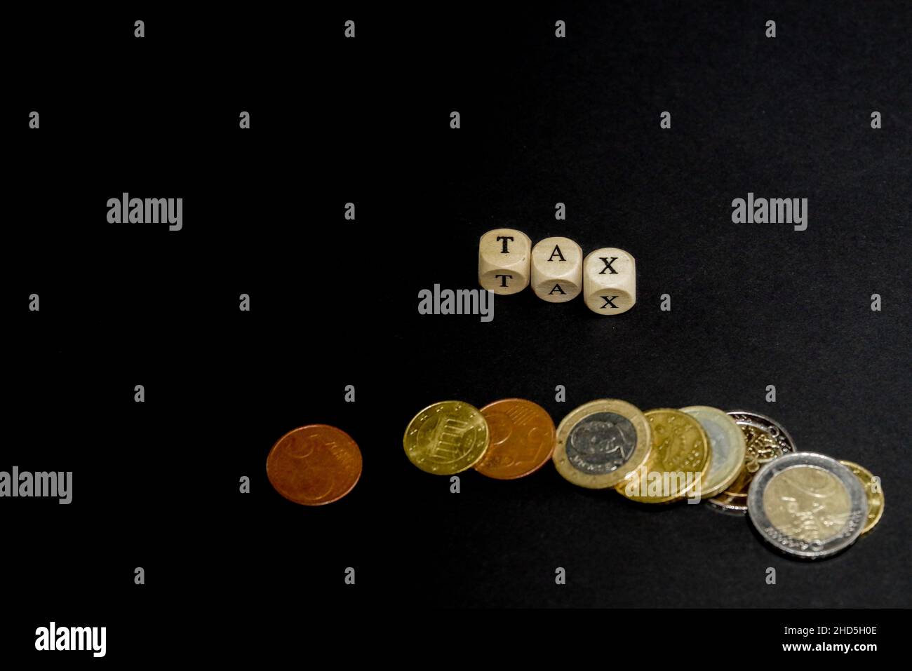 Several Euro coins with wooden letters cubes forming the word Tax in ...