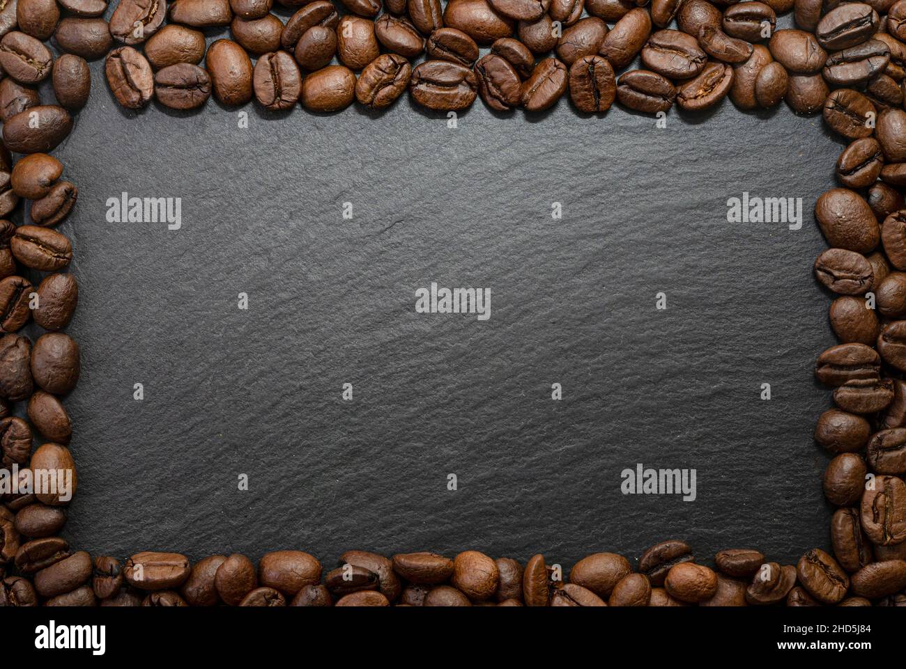 Composition of coffee beans frame on a black stone tile background ...