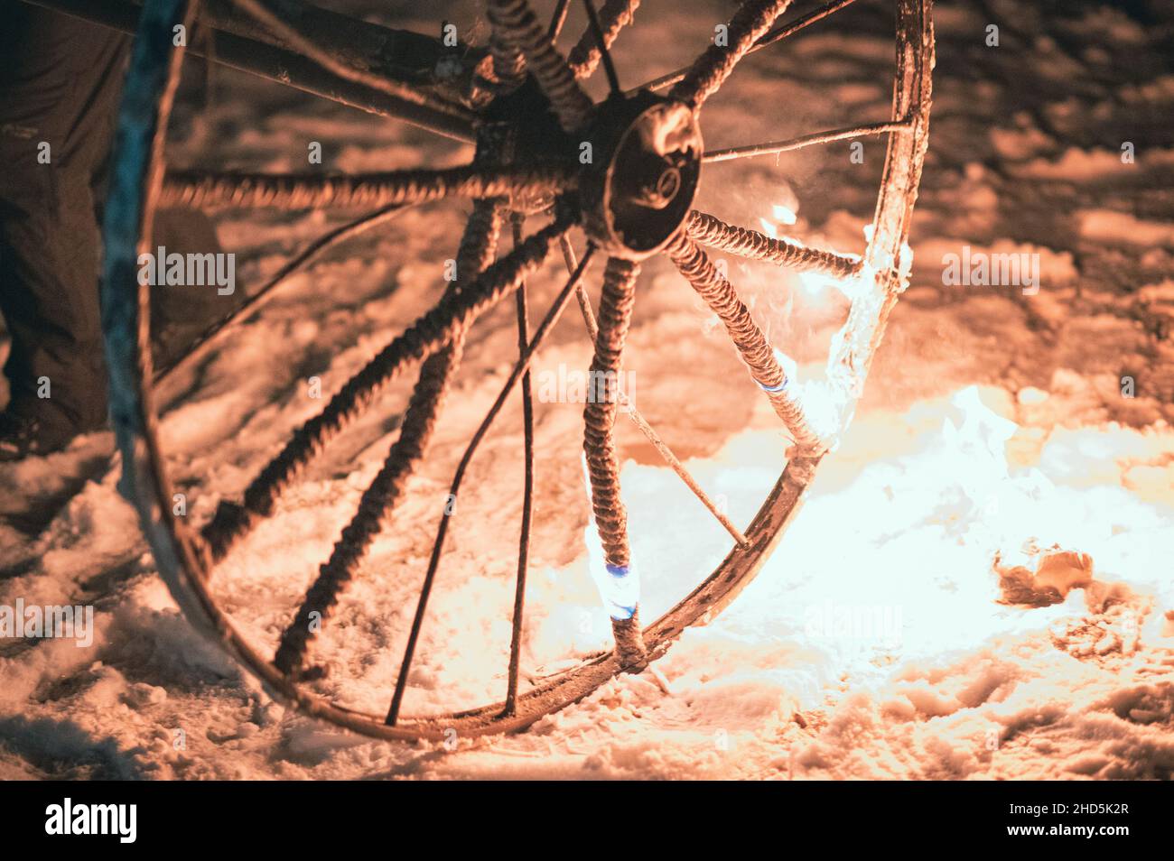 fire flames on an old cart wheel made of iron and spokes wrapped in ...