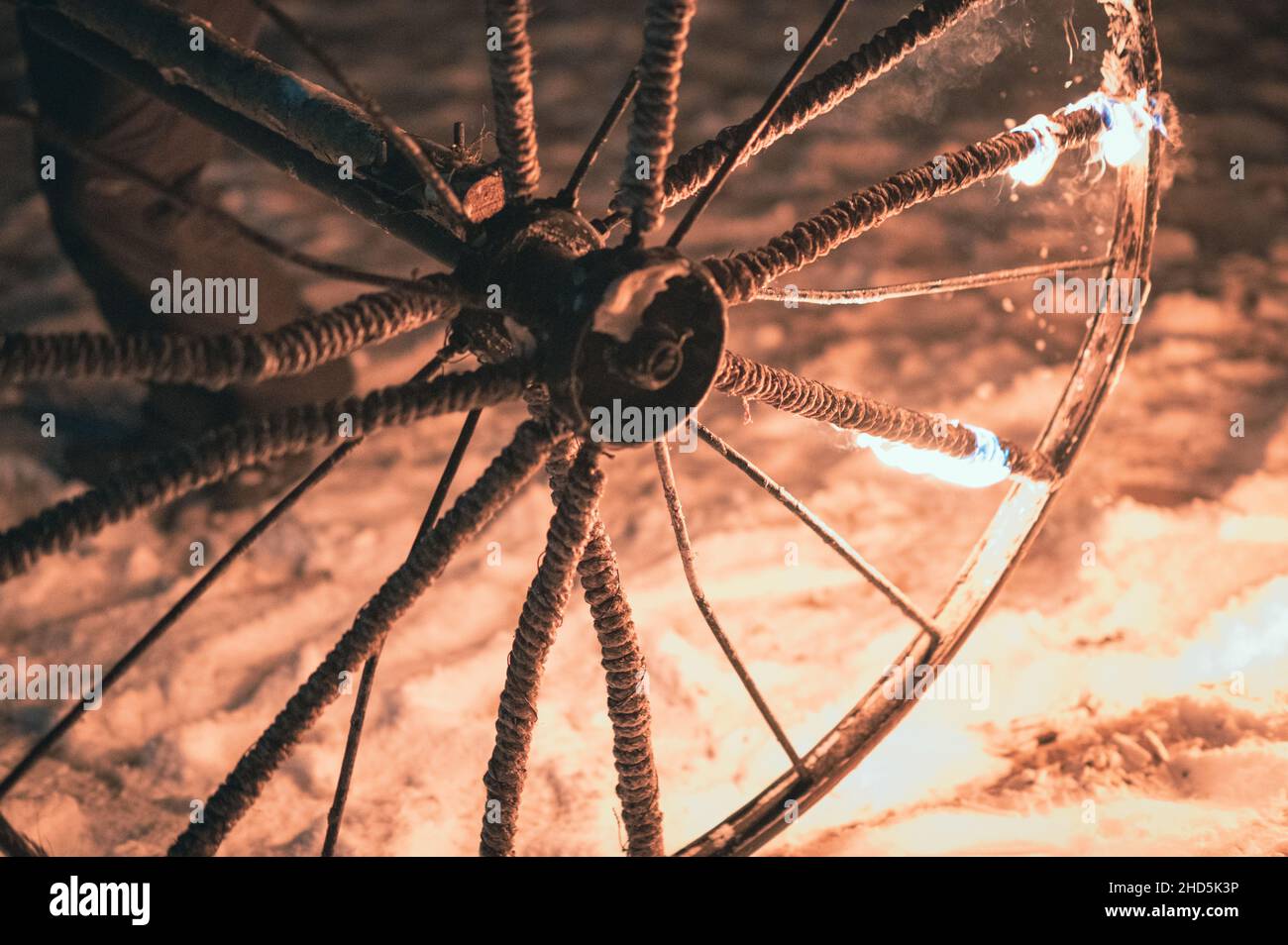 fire flames on an old cart wheel made of iron and spokes wrapped in ...
