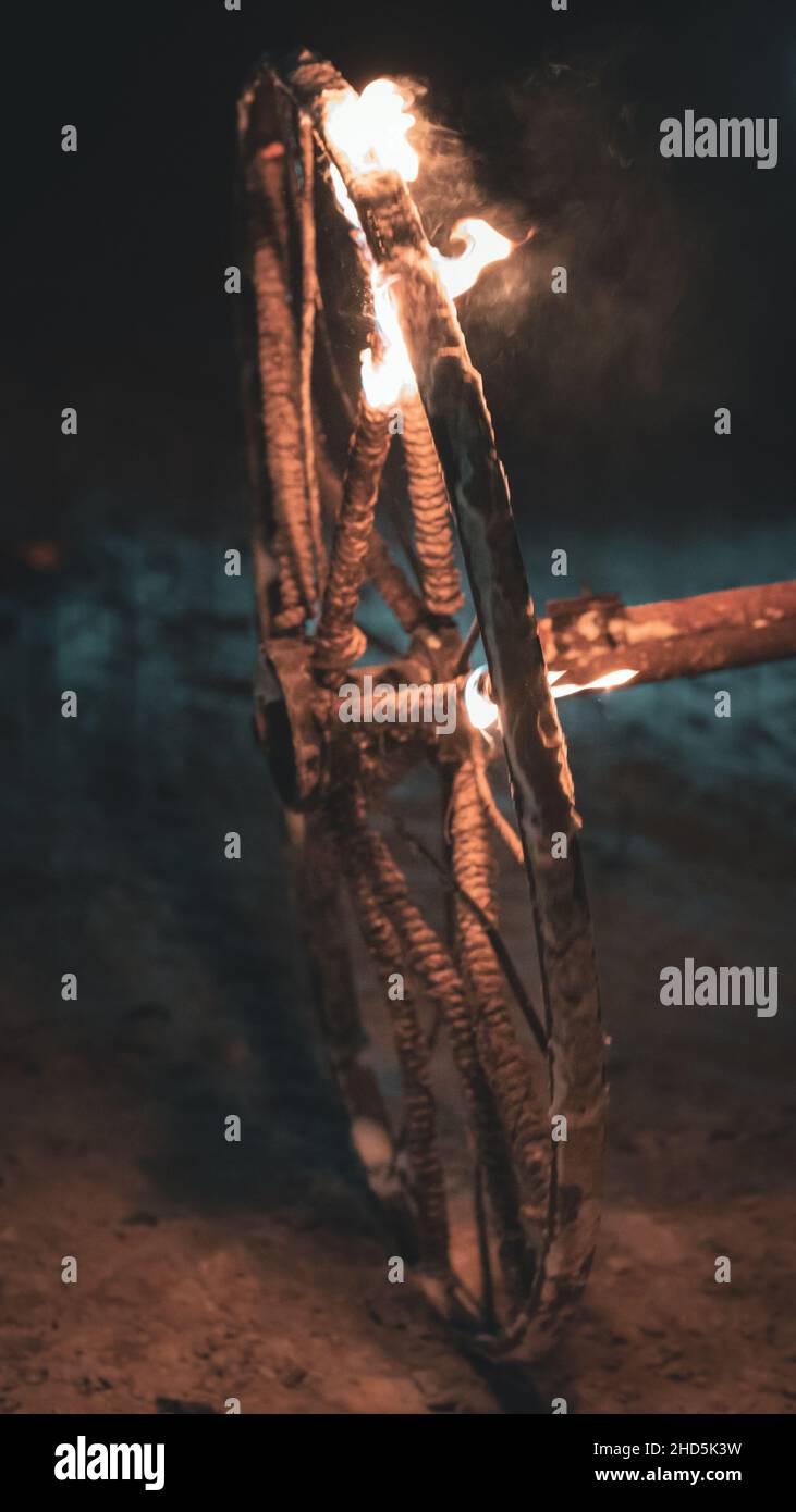 fire flames on an old cart wheel made of iron and spokes wrapped in ...