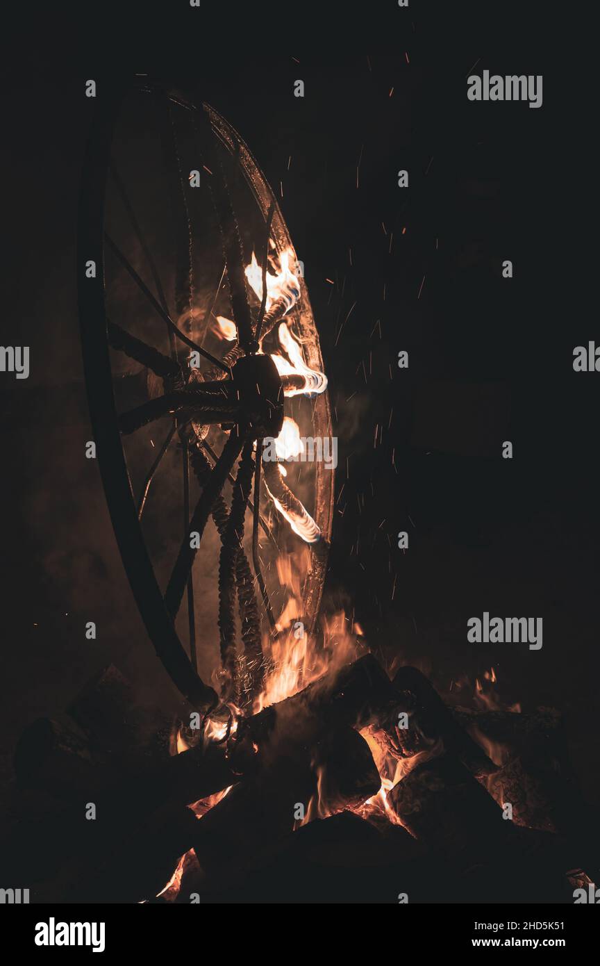 an old wheelchair burning in a fire with flames in the wheels in the ...