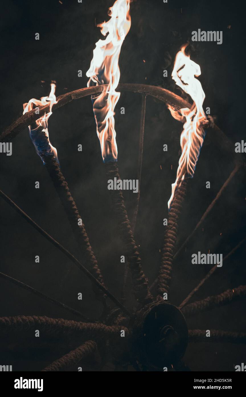 fire flames on an old cart wheel made of iron and spokes wrapped in ...