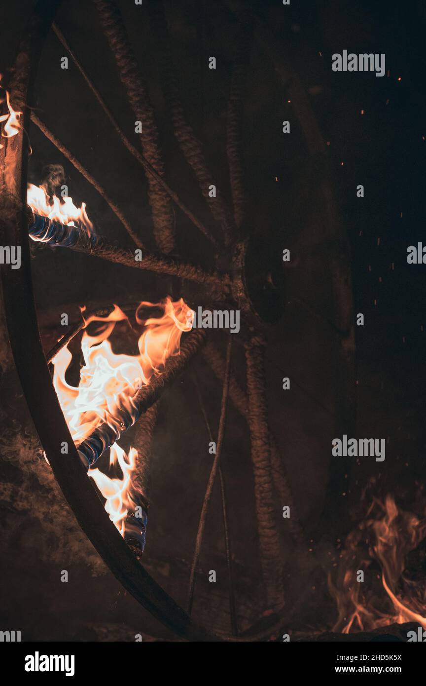 fire flames on an old cart wheel made of iron and spokes wrapped in ...