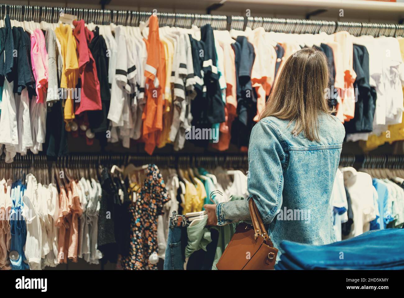 Woman in medical mask choosing clothes in outlet store Stock Photo - Alamy