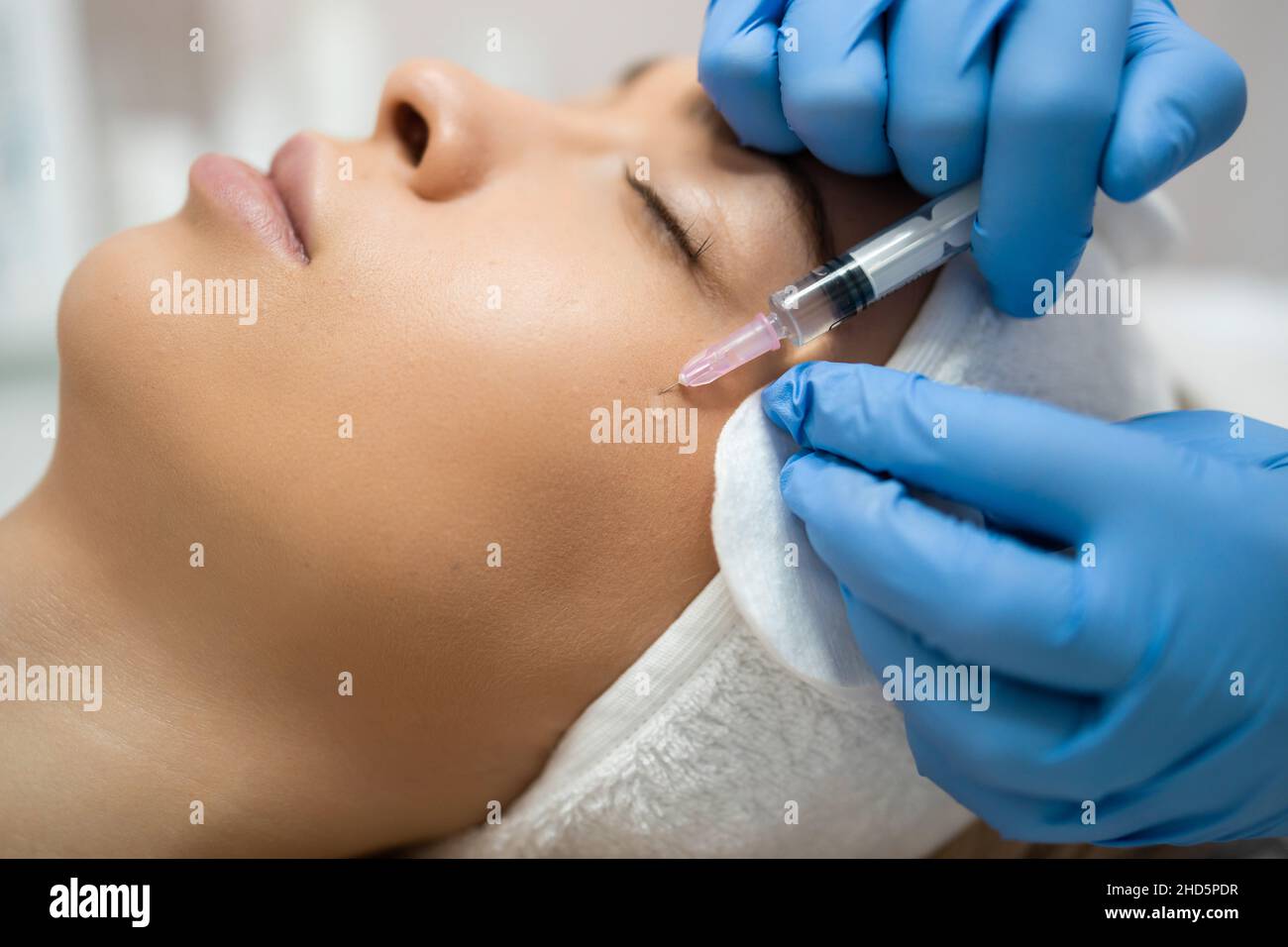 Woman in beauty salon getting botox injections to the cheek, close up ...