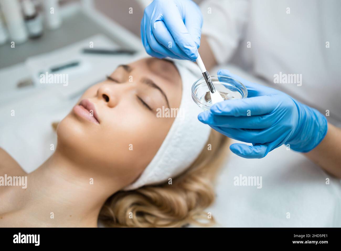 Doctor cosmetologist applies a transparent moisturizing mask to a woman ...