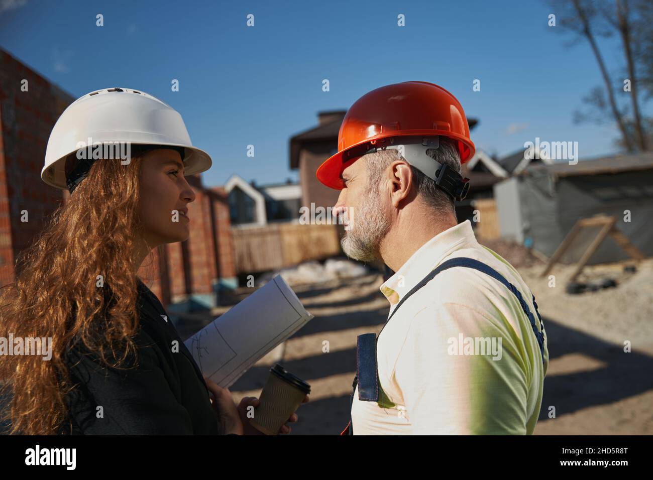 Engineer and construction worker looking at each other Stock Photo - Alamy