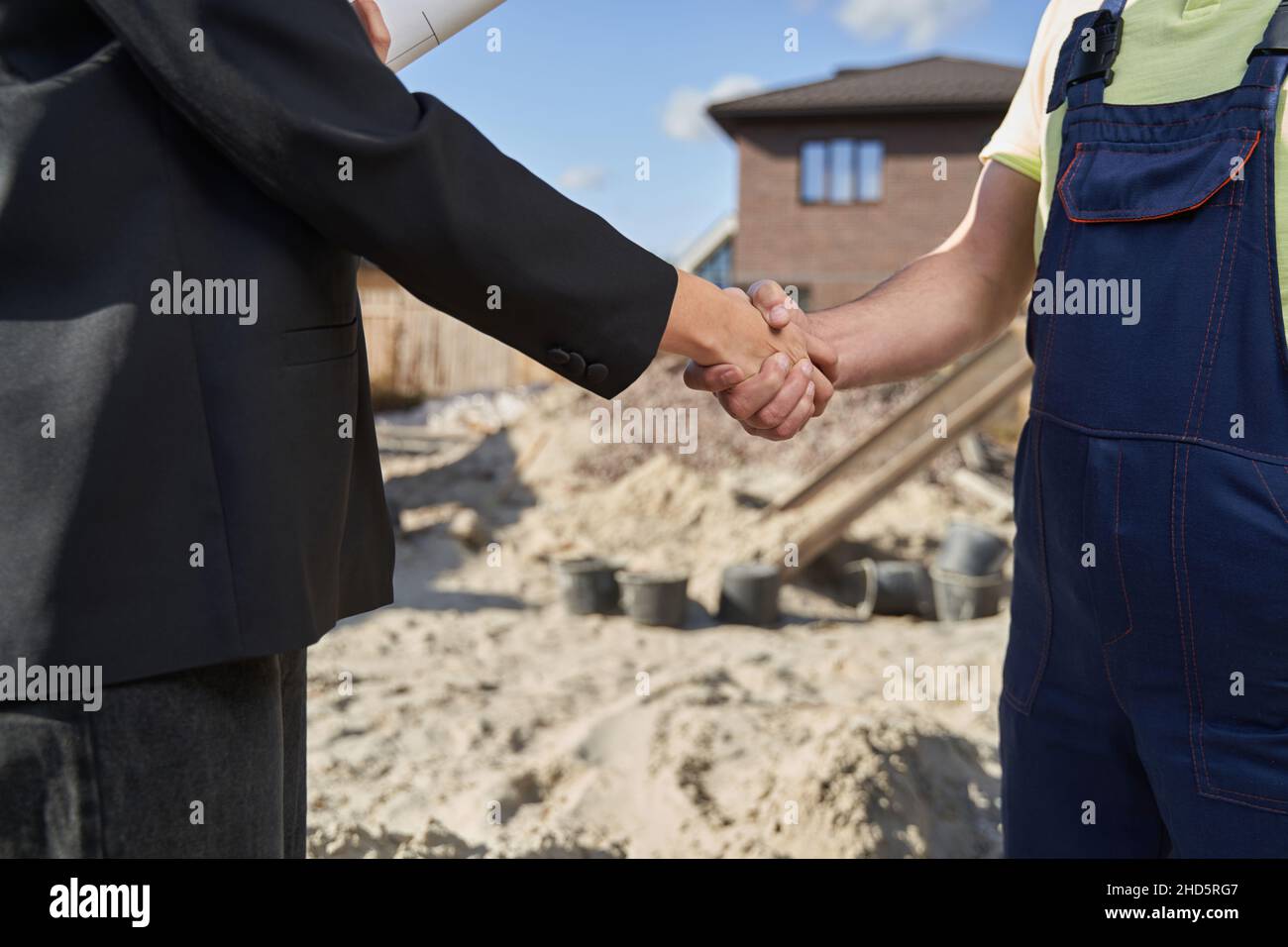 Two people shaking hands on construction area Stock Photo - Alamy