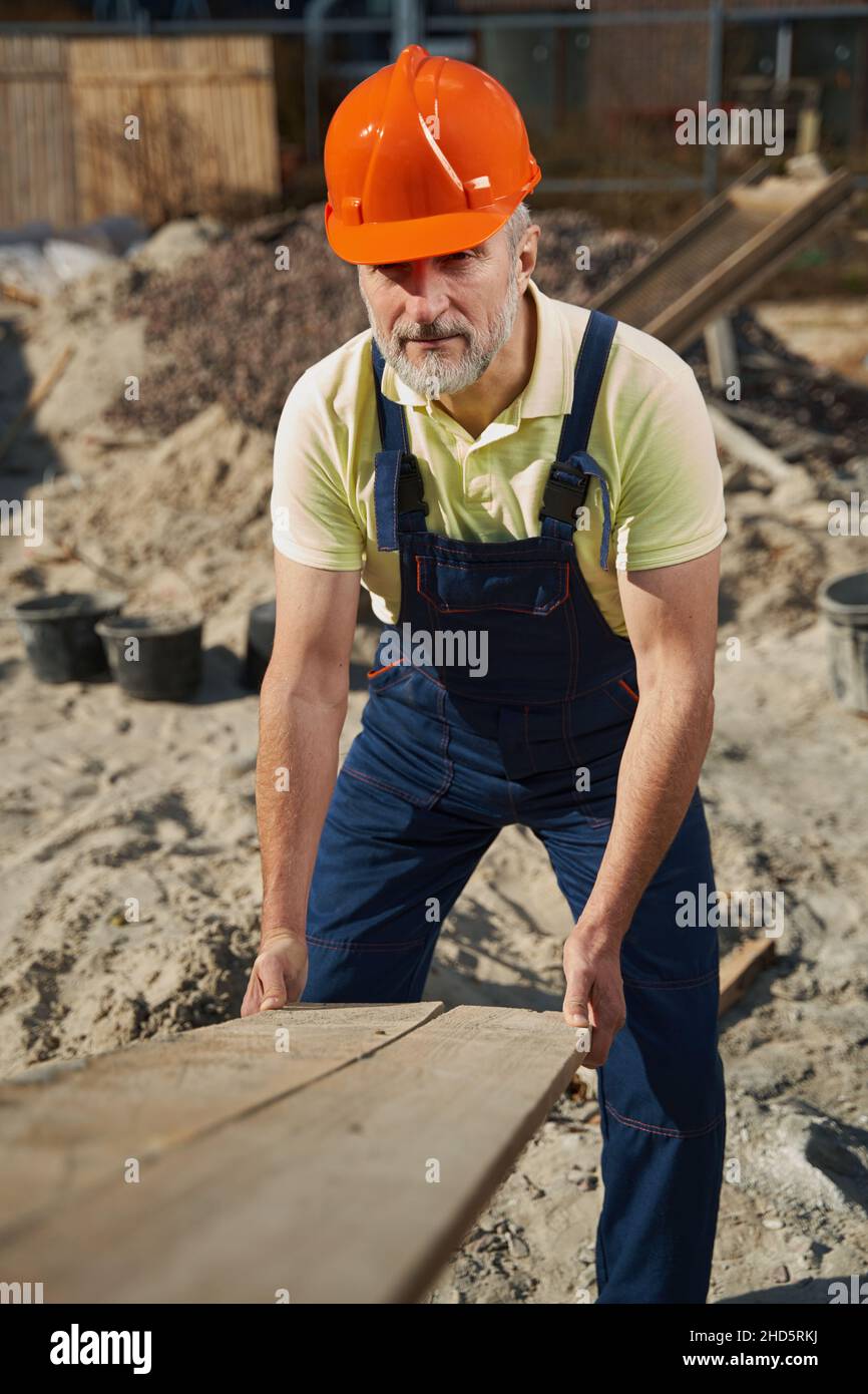 Worker putting plank end on ground at building area Stock Photo - Alamy