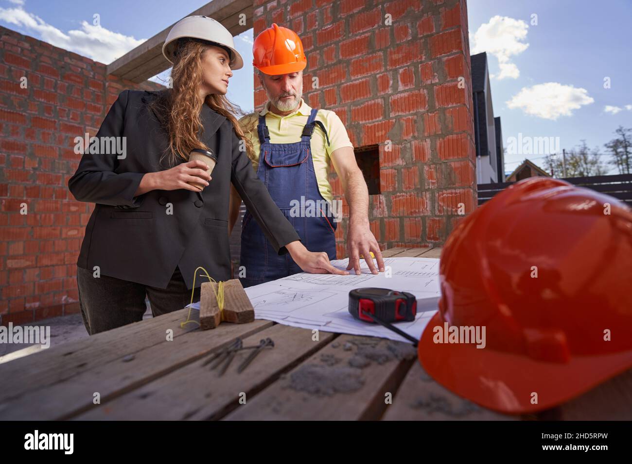 Female engineer pointing at blueprint to constructino worker Stock ...