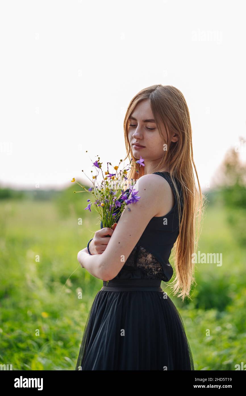 Portrait of a Russian girl with a bouquet of wild flowers in the ...