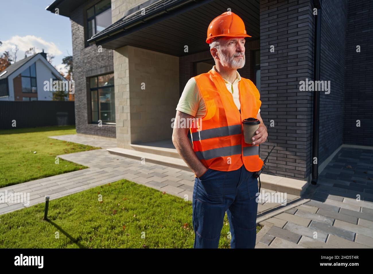 Serious construction worker with coffee staring into distance Stock ...