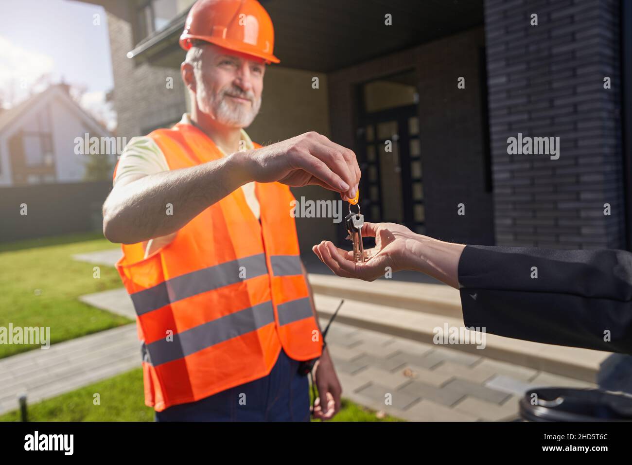 Male construction worker passing keys to house Stock Photo - Alamy
