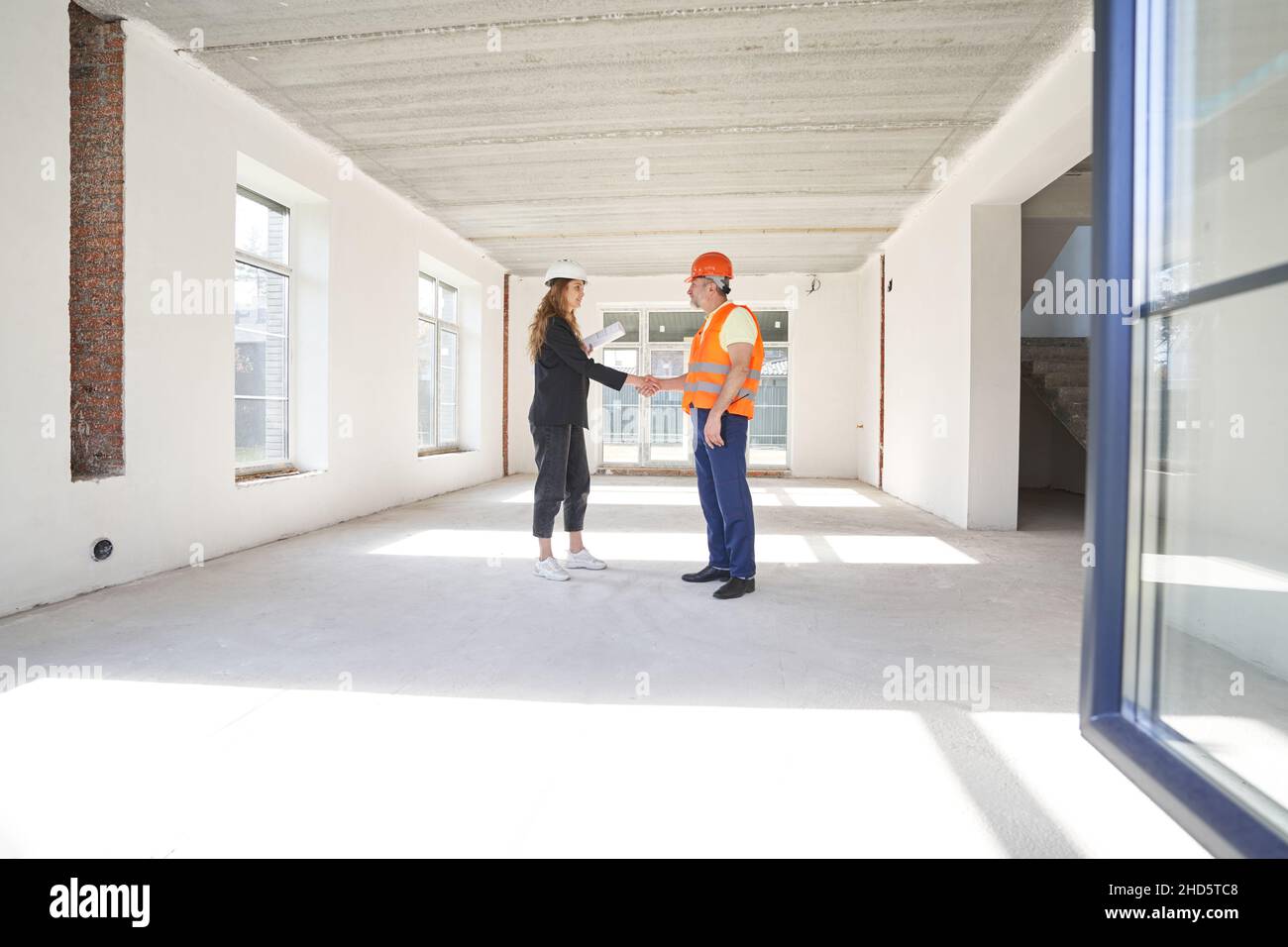 Woman construction engineer shaking hands with worker in room Stock ...