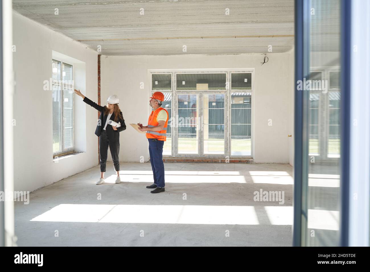 Builder taking notes from female engineer about window Stock Photo - Alamy