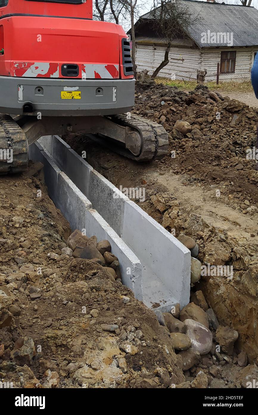 The excavator installs concrete trays for drainage of rainwater in ...