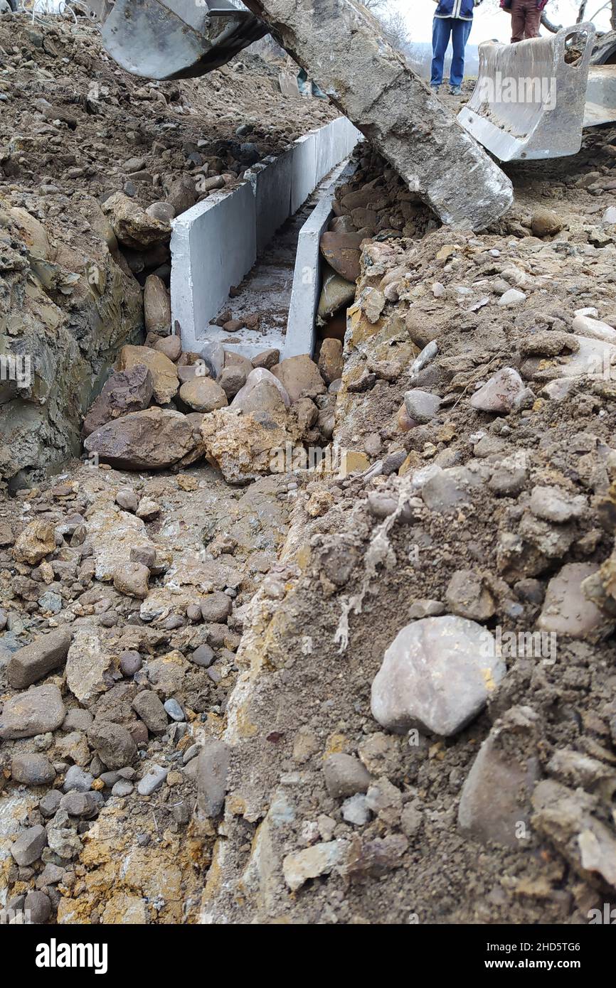 The excavator puts concrete slabs for moving through the gutter ...