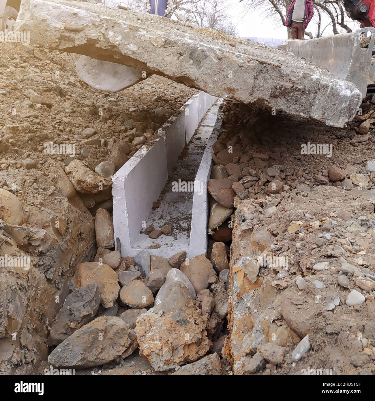 The excavator installs concrete trays for drainage of rainwater in ...