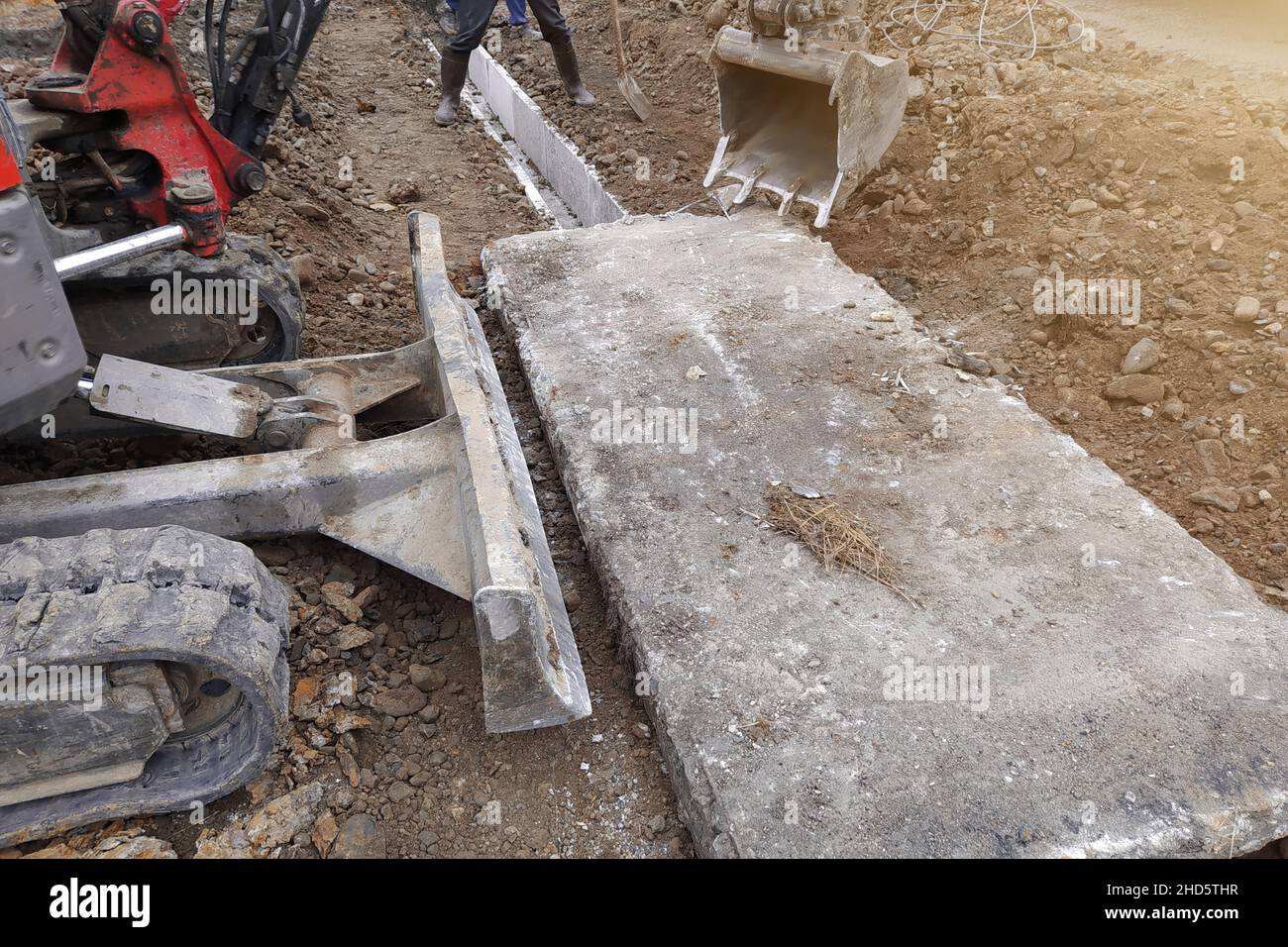 The excavator puts concrete slabs for moving through the gutter ...