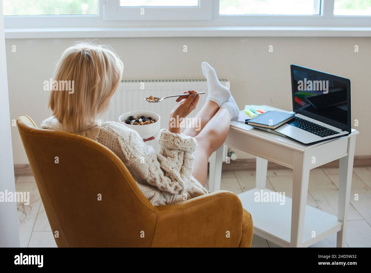 Back rear view. Woman working from home on laptop while eating the meal ...