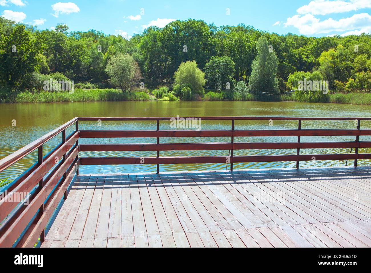Observation deck with wooden balustrade at the lake . Pond on a summer ...